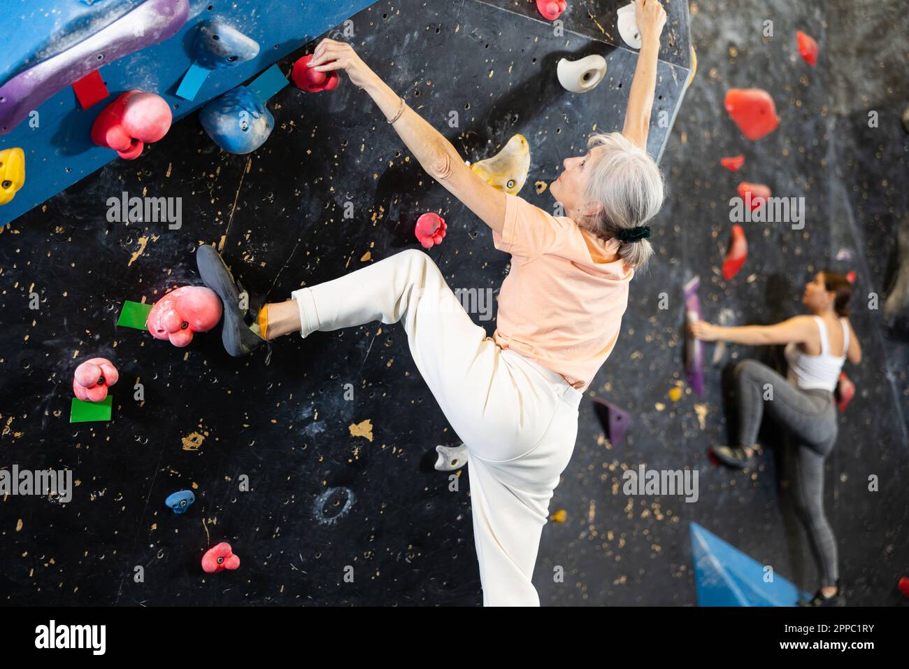 Joyful concentrated senior woman busy with her hobby bouldering ...