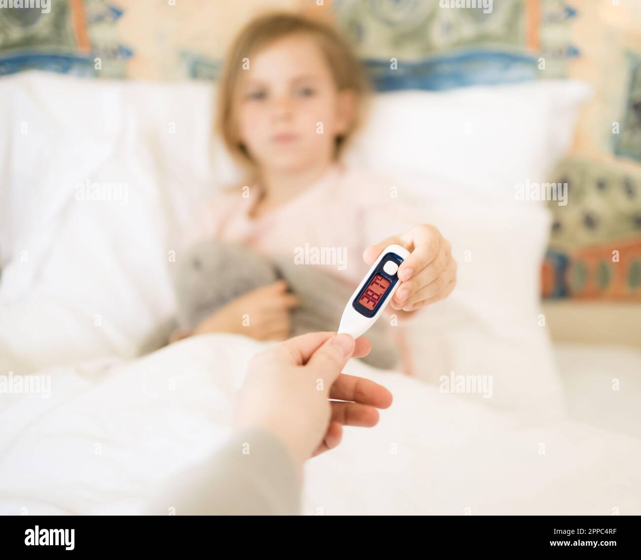 Little girl giving to her mother digital thermometer after measuring temperature. Sick child has ...