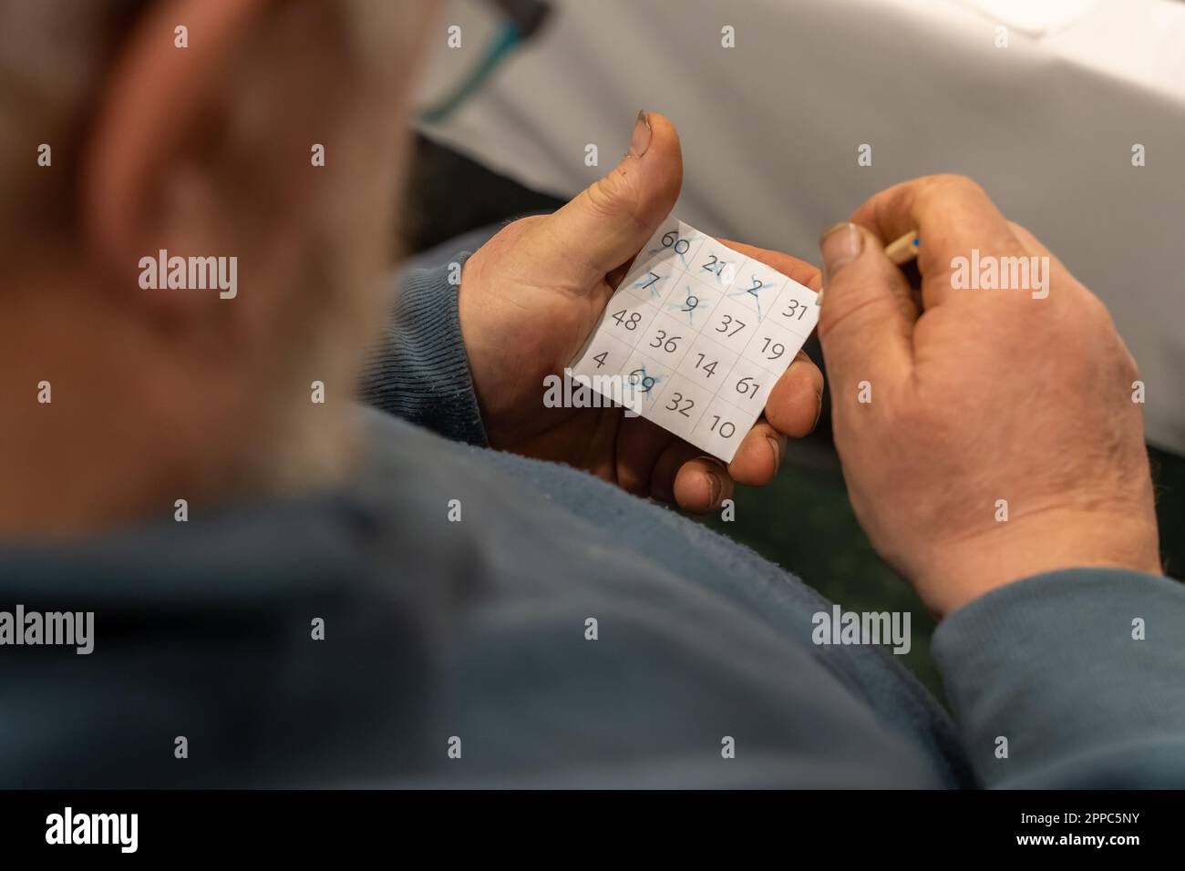 Over the shoulder view of old man holding bingo card with numbers ...