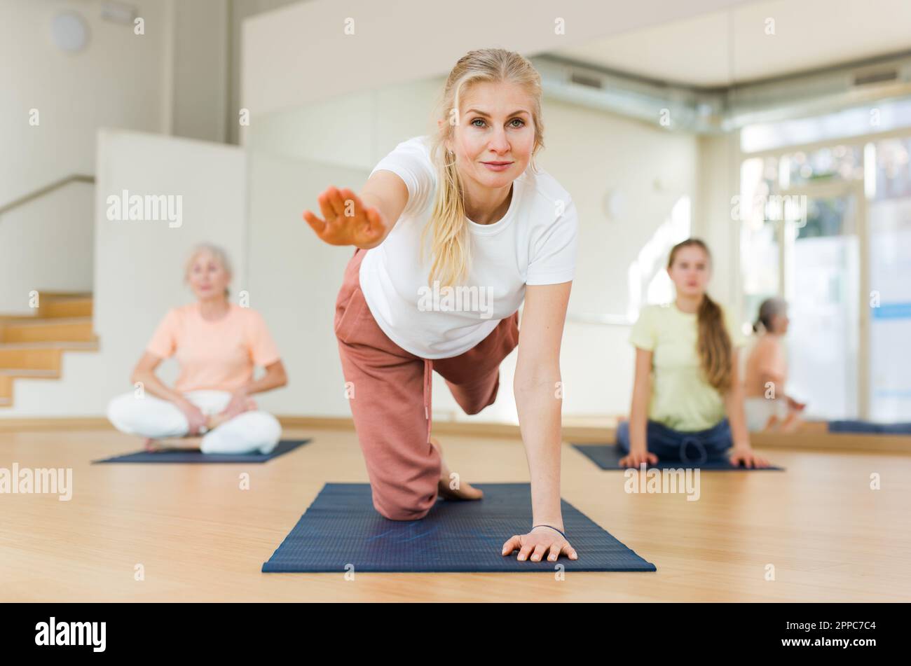 Family of three generations exercising Hatha yoga poses in yoga studio ...