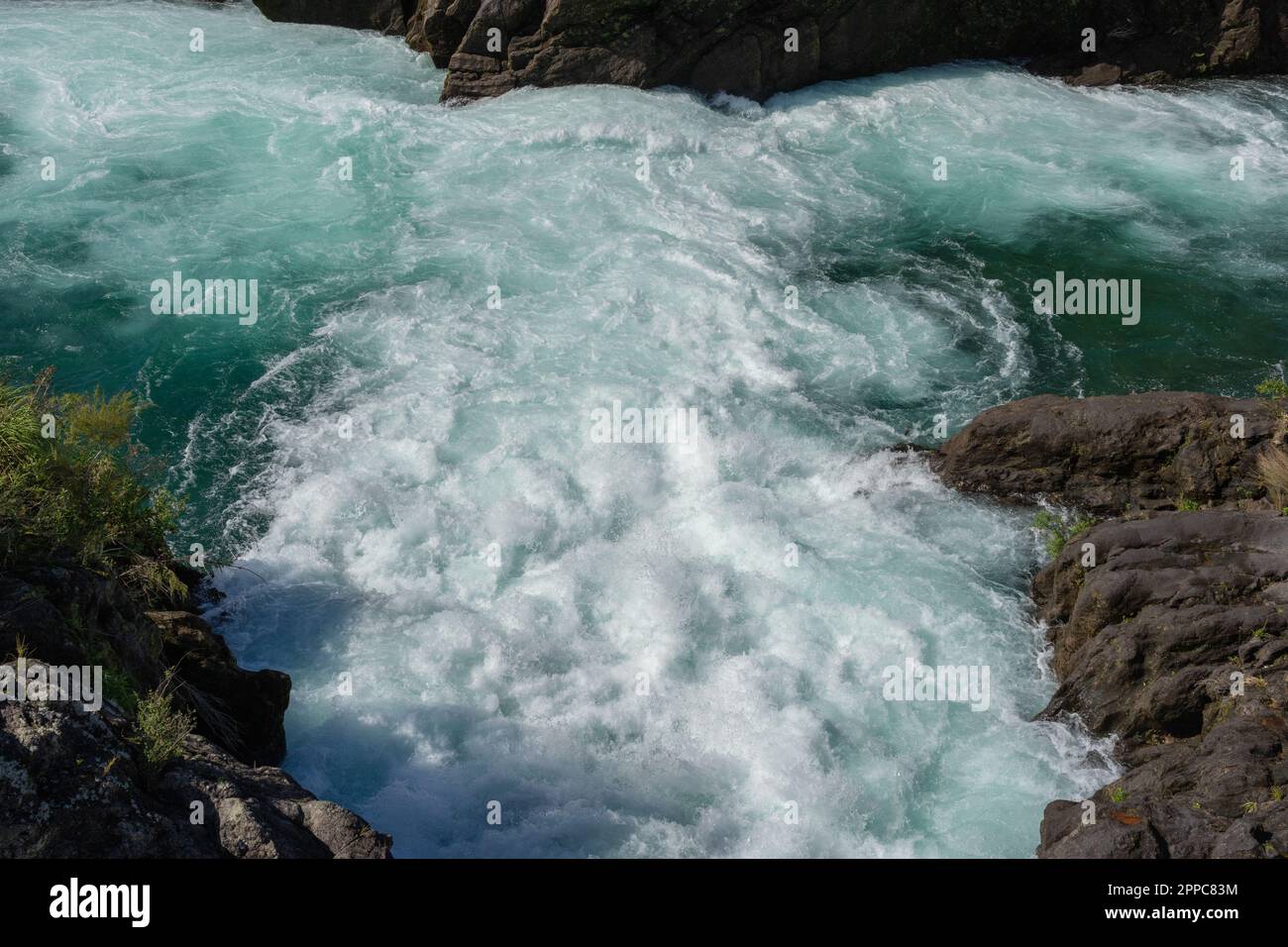 Swirling and surging river water through rocks below as the dam gates ...