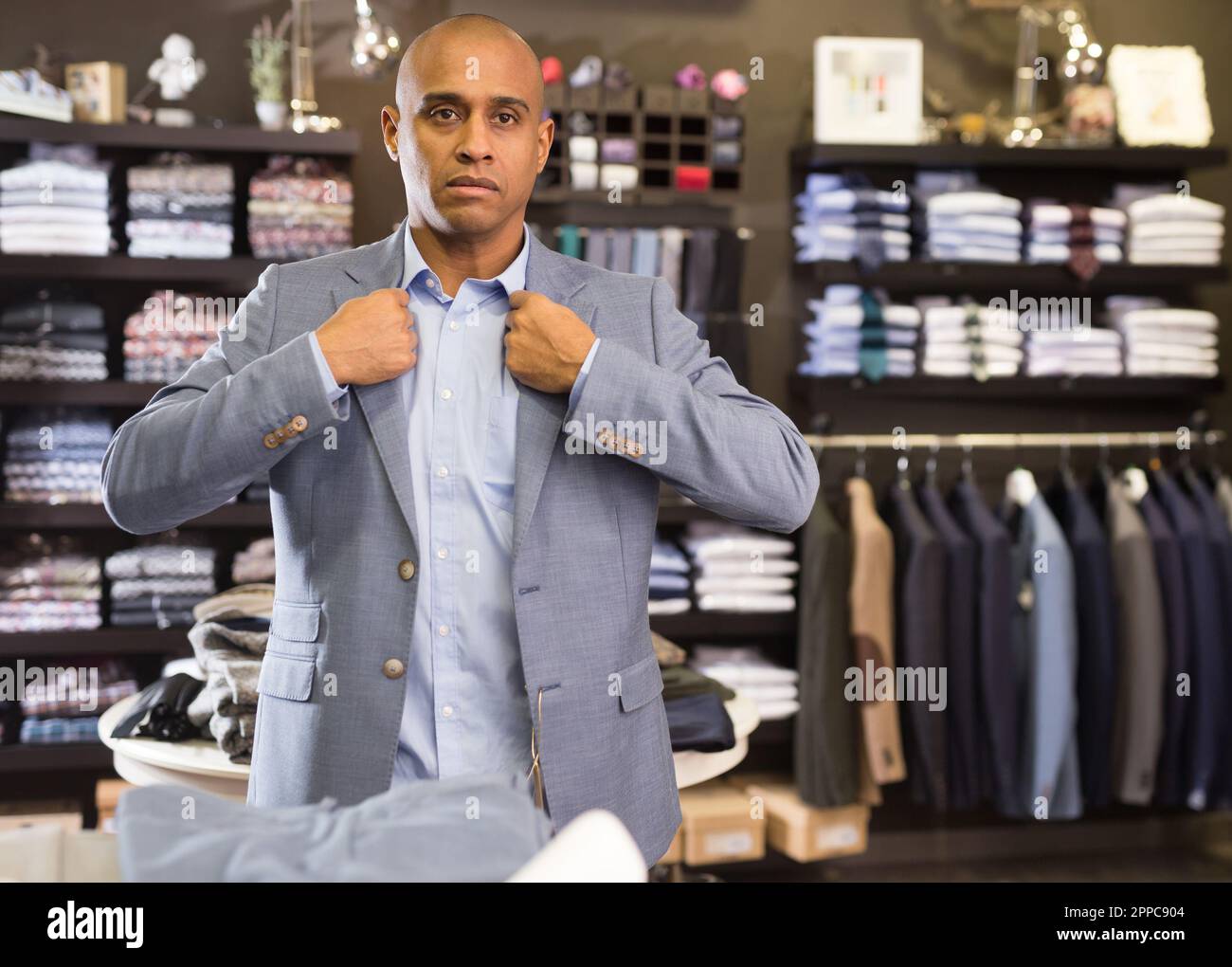 Man choosing suit jacket in clothing store Stock Photo - Alamy