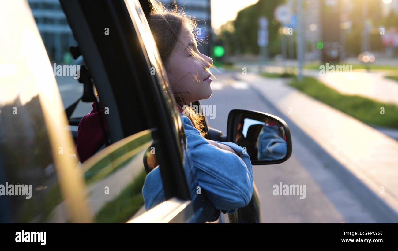 Happy cute Caucasian girl enjoying in car traveling in city on road ...