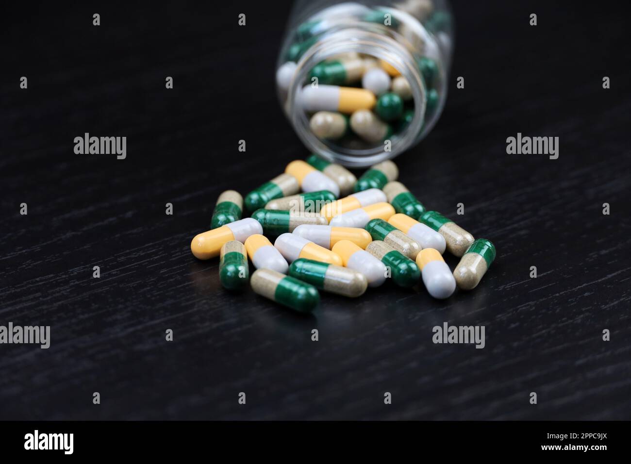 Pills on a black wooden table, variation of medication in capsules ...