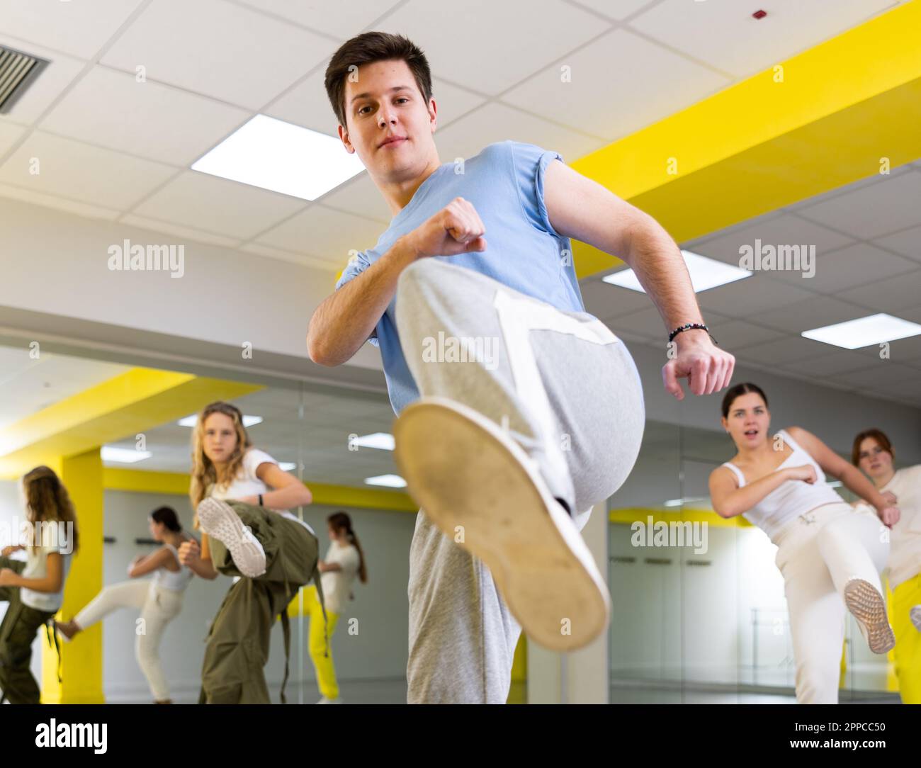 Ordinary teen girls and boy performing kick step movement during ...