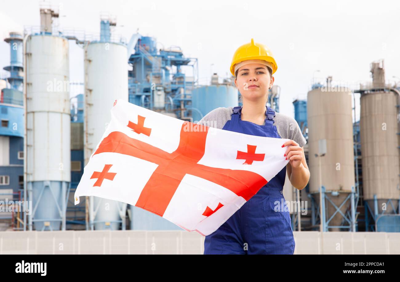 Young female engineer in helmet waving state flag of Georgia while ...