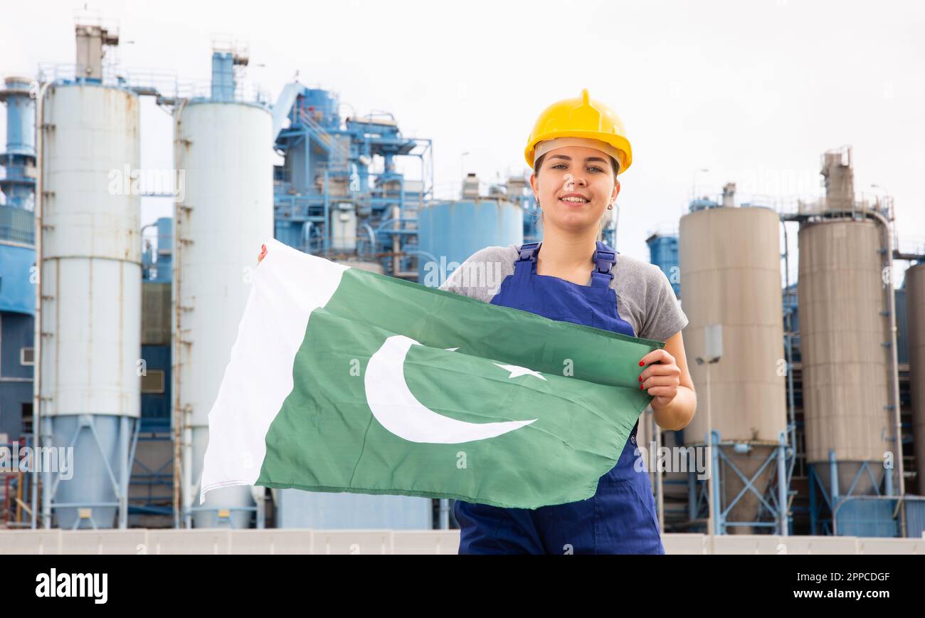 Young female engineer in helmet waving state flag of Pakistan while ...