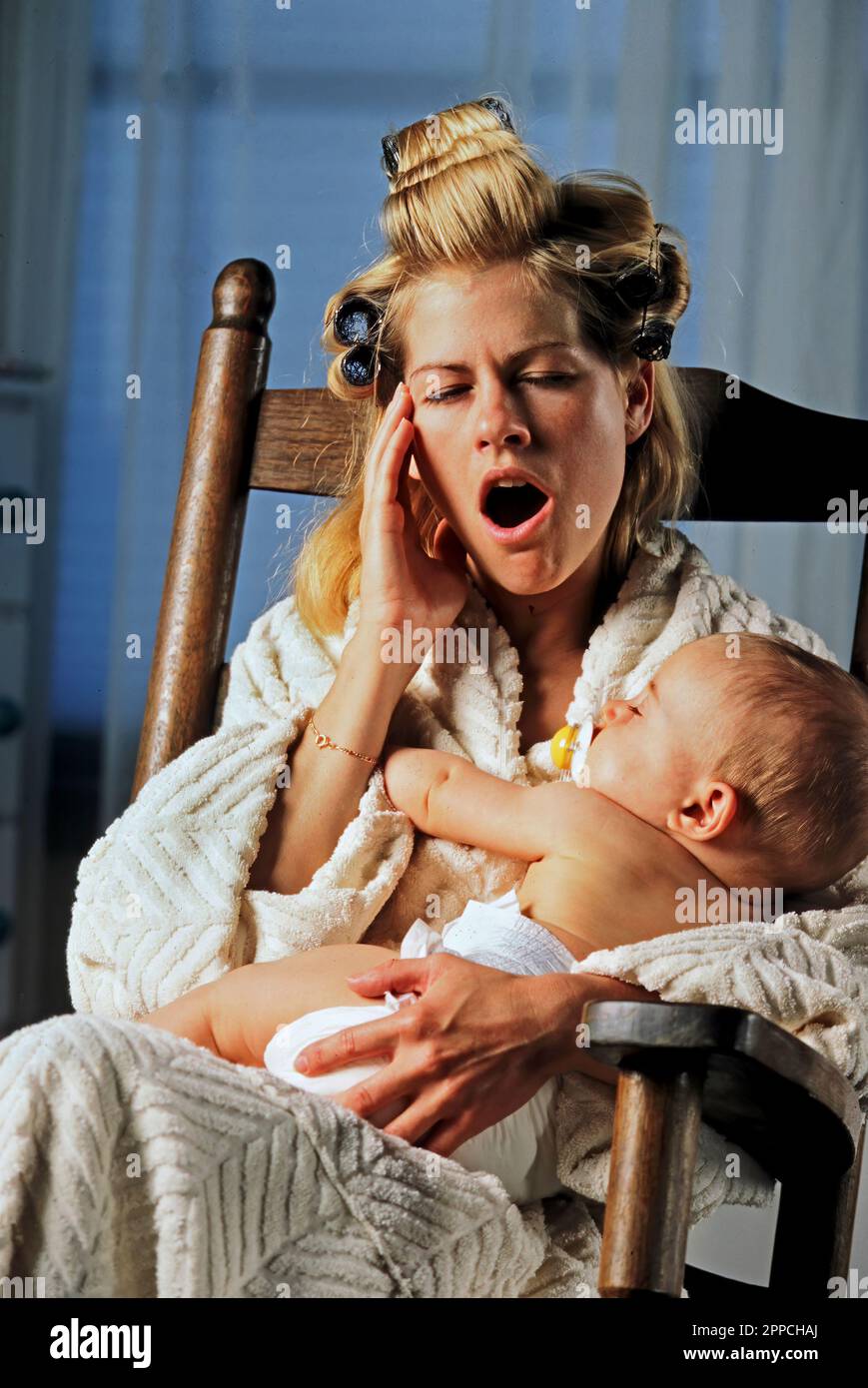 Young sleepless mother in a rocking chair with crying newborn baby i ...