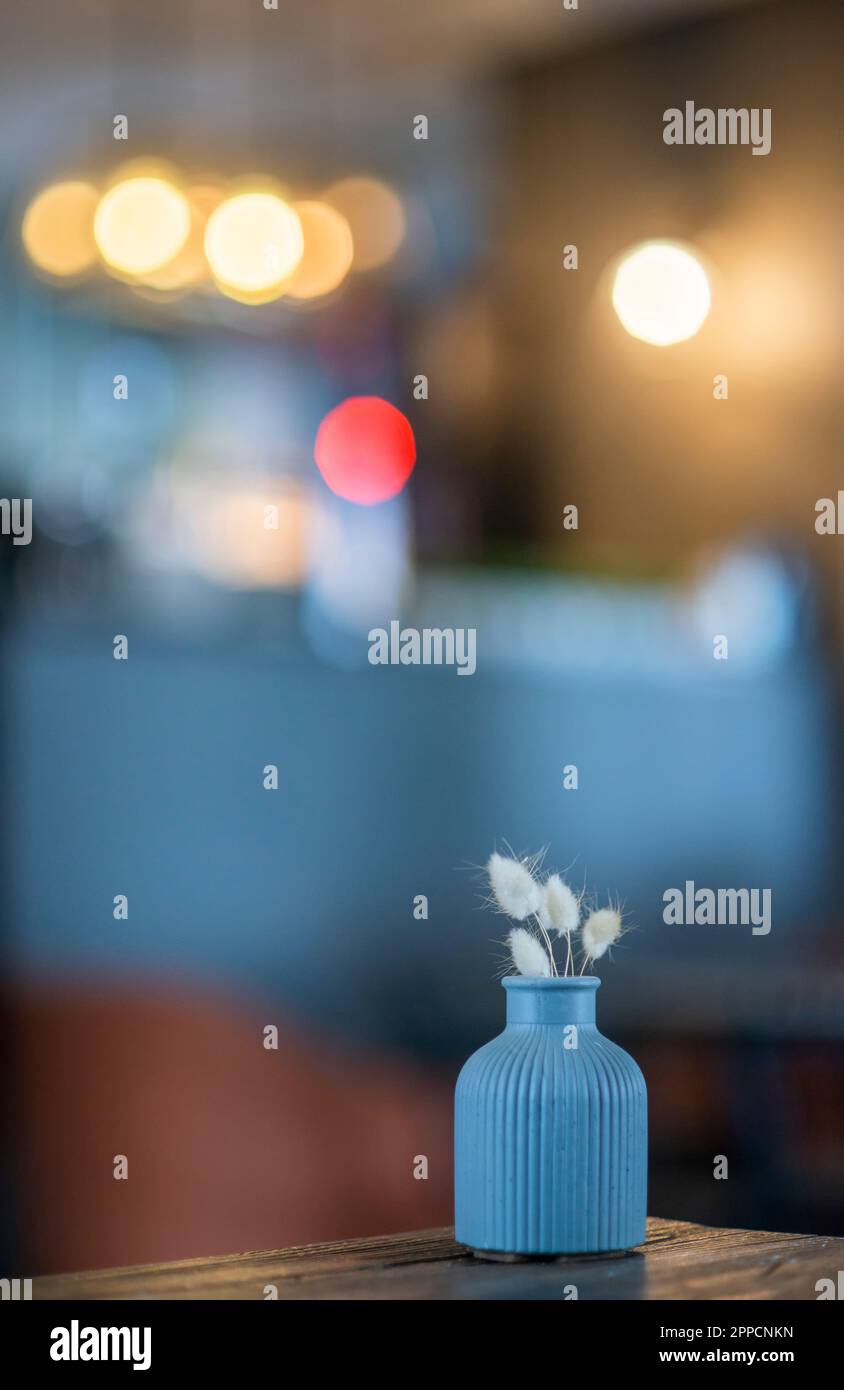 Small blue minimalistic ceramic vase on a table at a cafe with dried ...