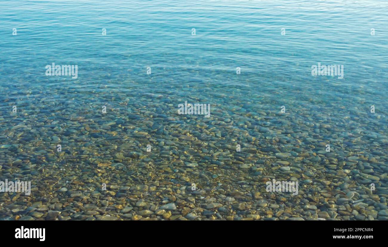 A calm transporent water surface with pebbles stone under water surface ...
