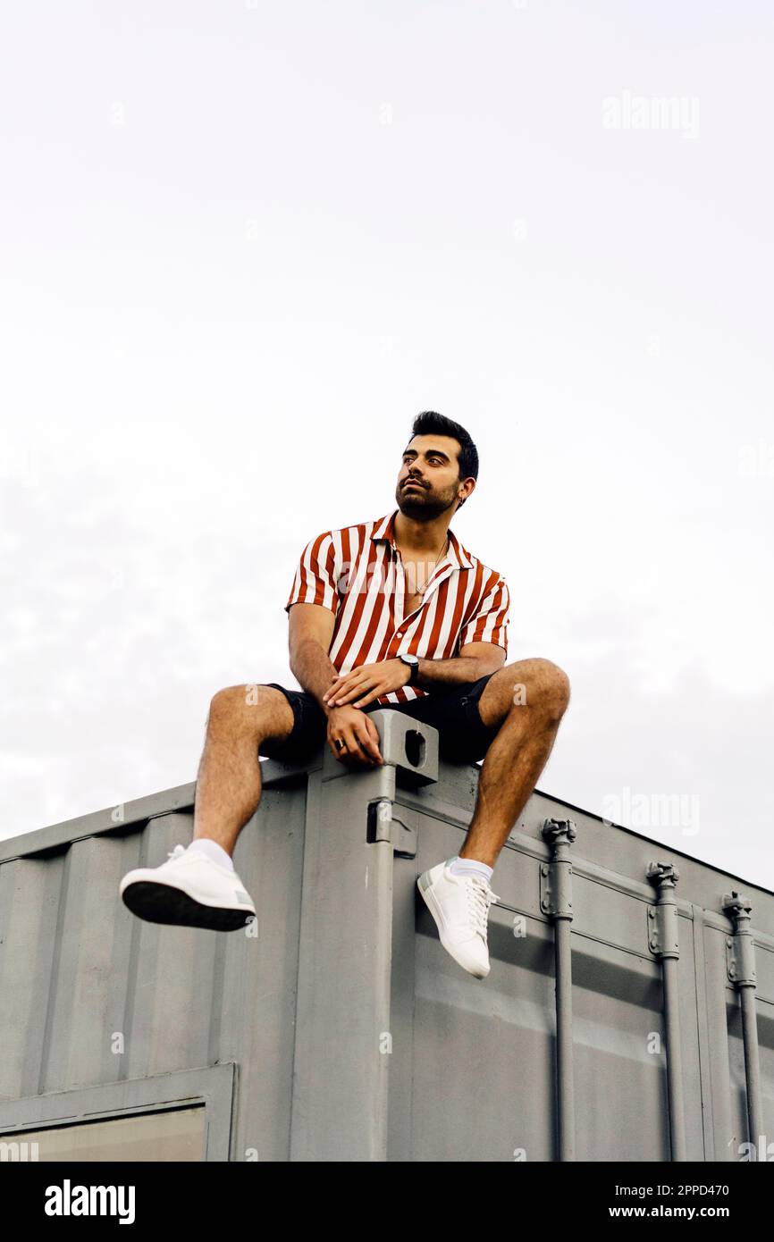 Contemplative man sitting on top of container home Stock Photo - Alamy