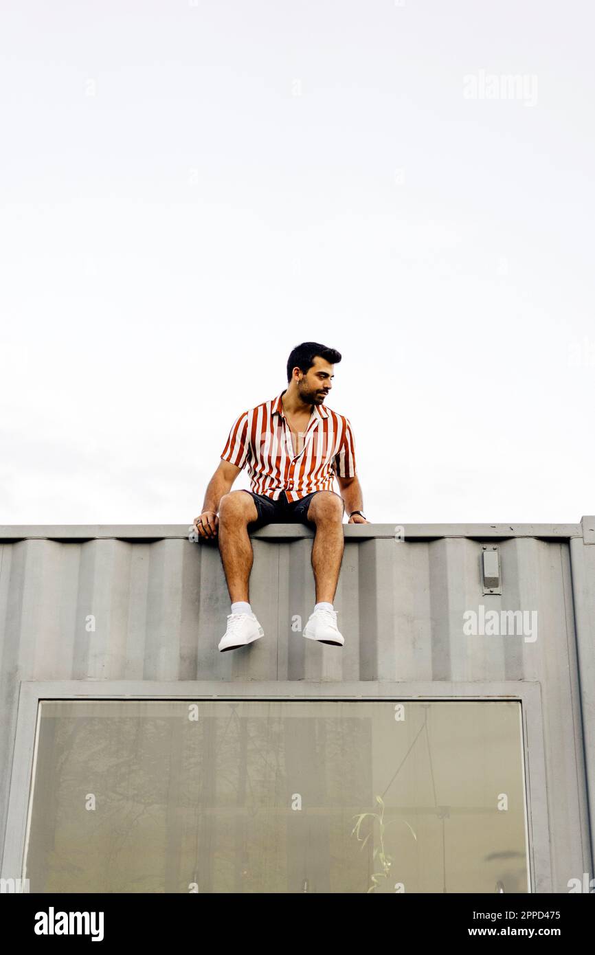 Man sitting on top of container home Stock Photo - Alamy