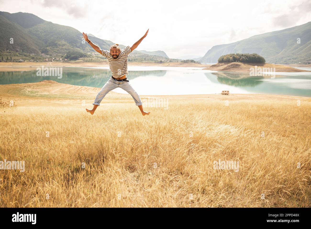 Carefree man jumping in front of lake Stock Photo - Alamy