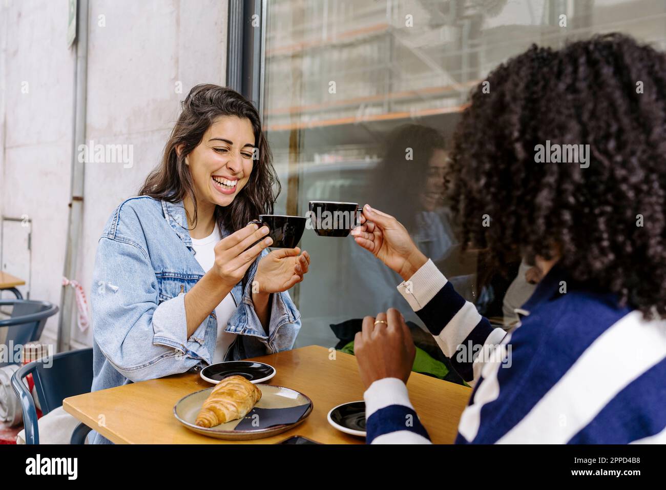 Cheerful young friends toasting coffee cup and enjoying at sidewalk ...