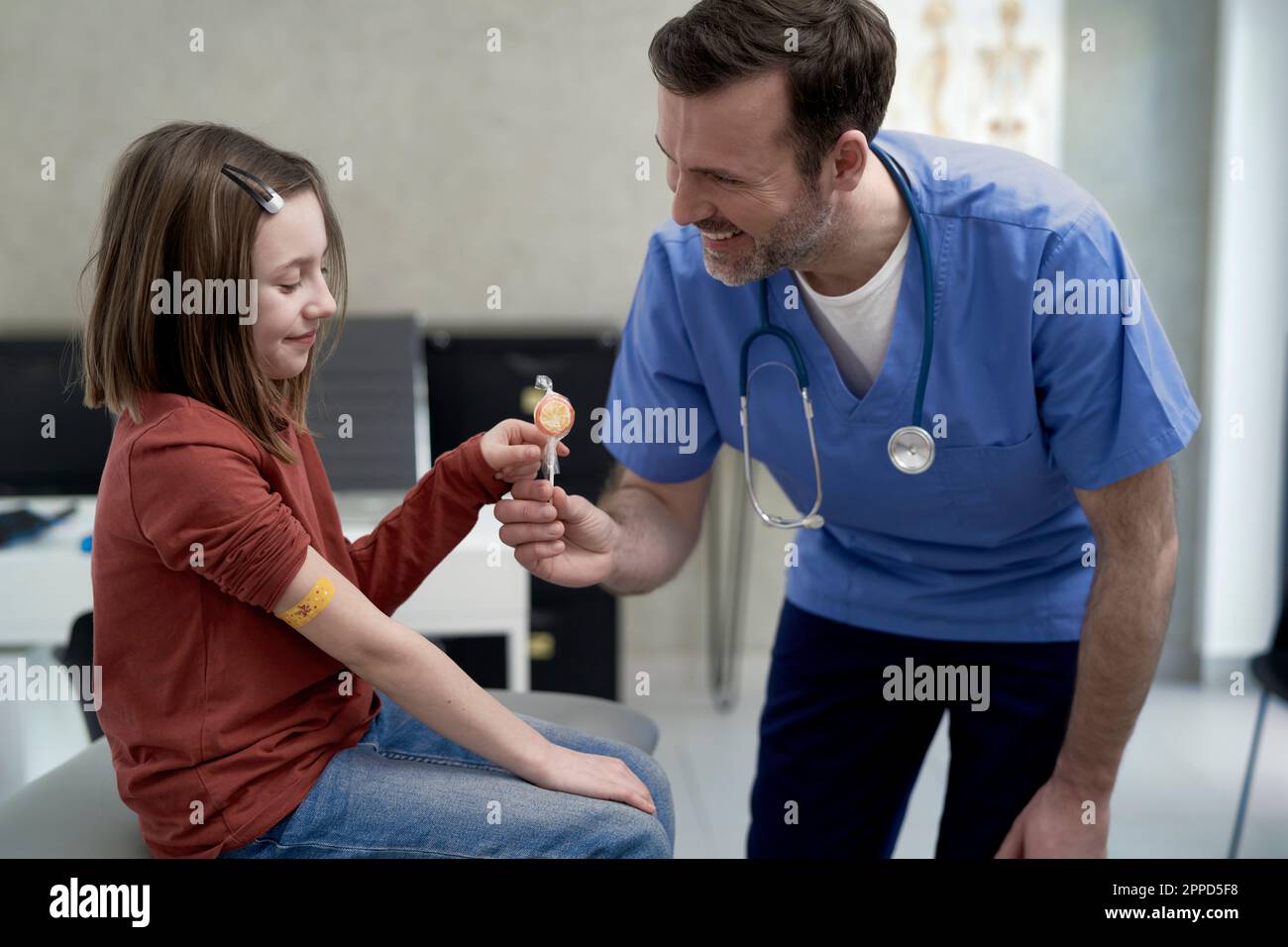 Happy mature doctor giving lollipop to girl in clinic Stock Photo - Alamy