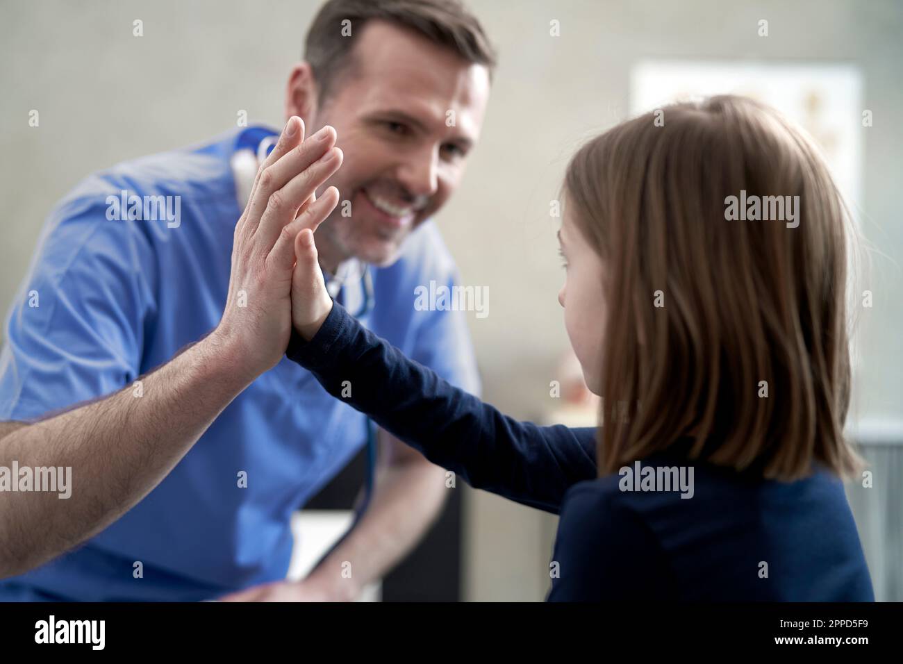 Happy doctor giving high-five to girl in clinic Stock Photo - Alamy