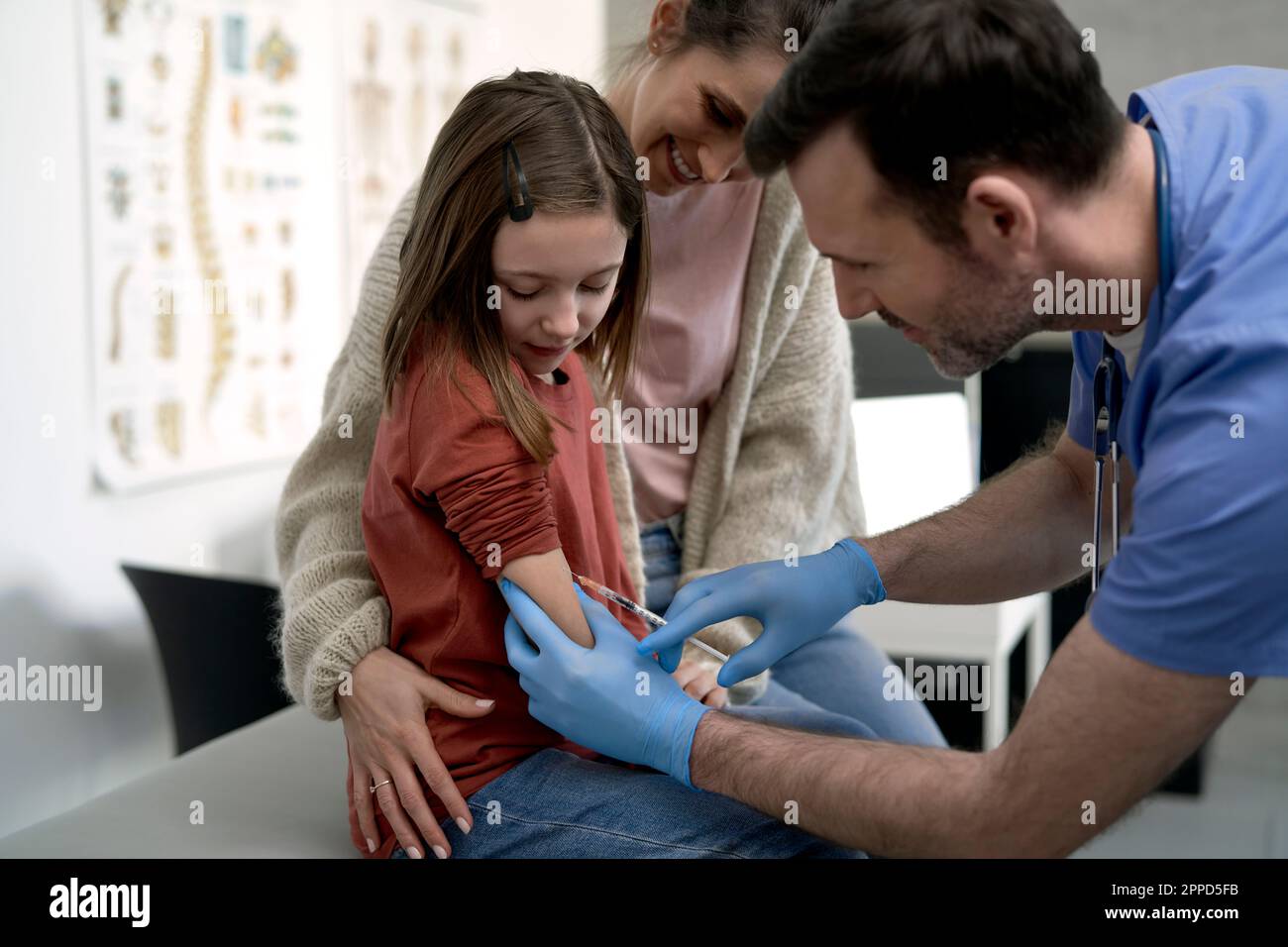 Doctor injecting syringe in girl's arm at clinic Stock Photo - Alamy