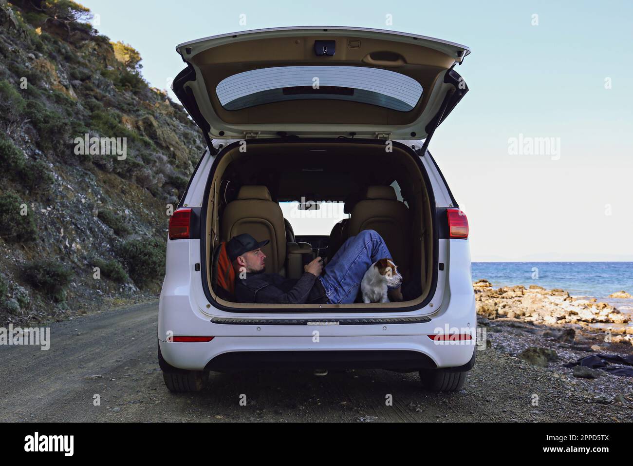 Man using smart phone lying down in car trunk at vacation Stock Photo ...