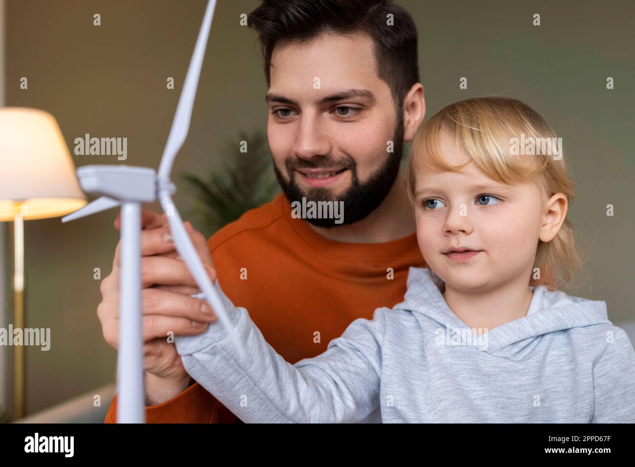 Smiling father teaching about wind turbine to son at home Stock Photo ...
