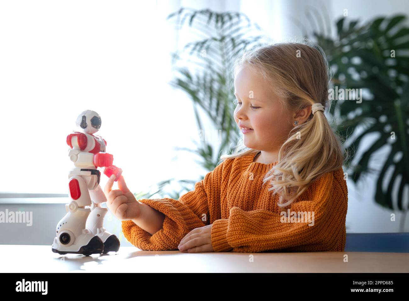 Smiling girl playing with robot at home Stock Photo - Alamy