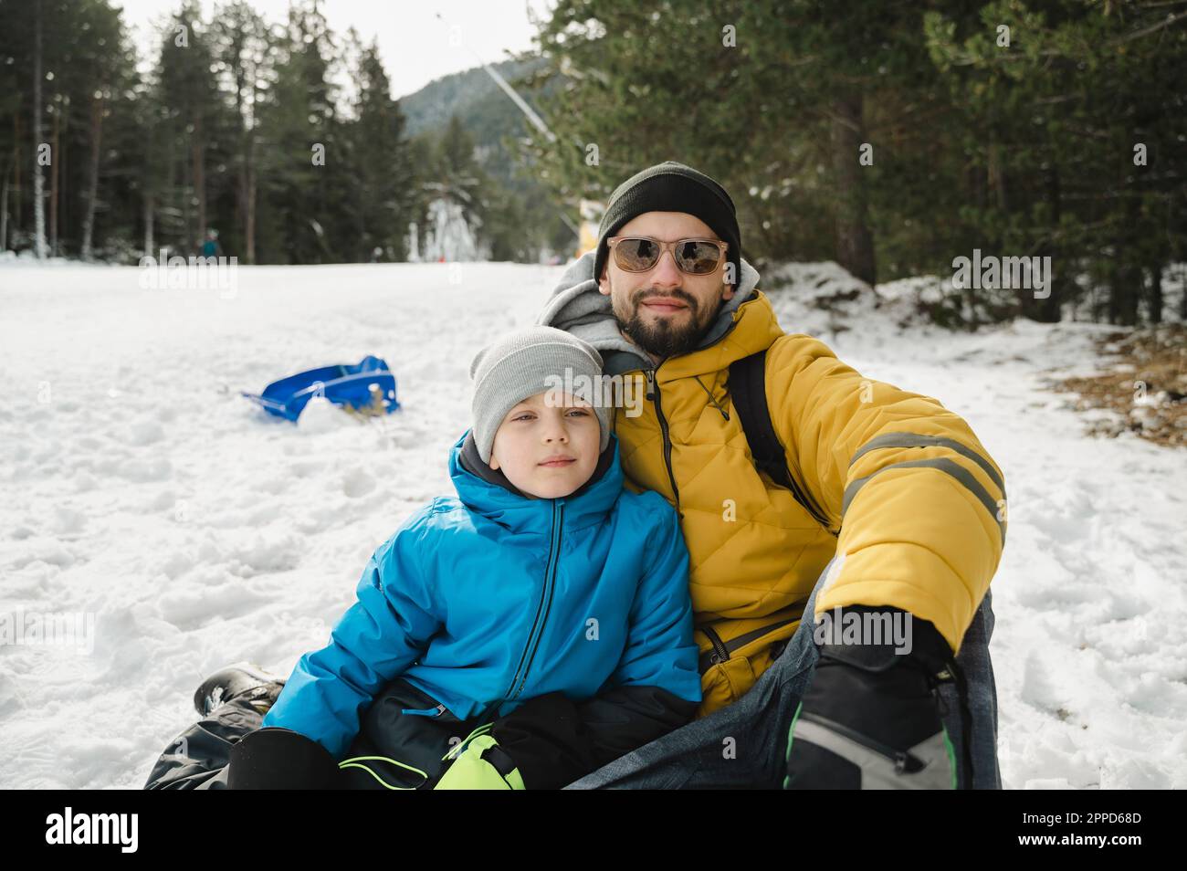 Father and son sitting in snow Stock Photo - Alamy