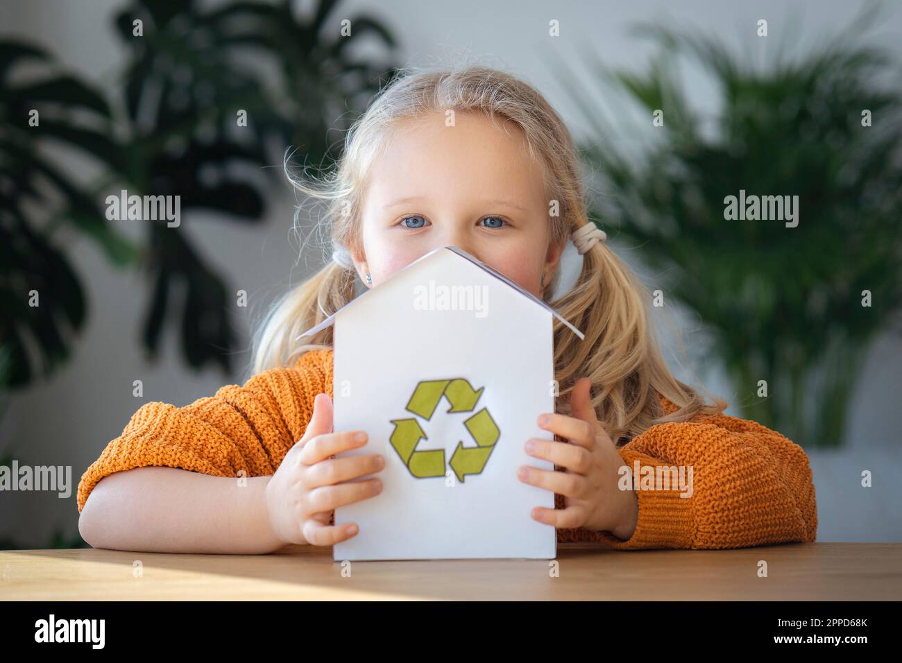 Blond girl holding house model with recycling logo Stock Photo - Alamy