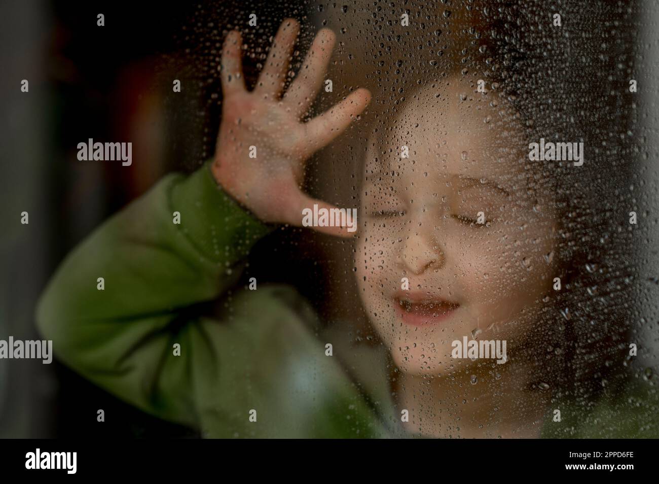 Boy touching face on wet glass Stock Photo - Alamy