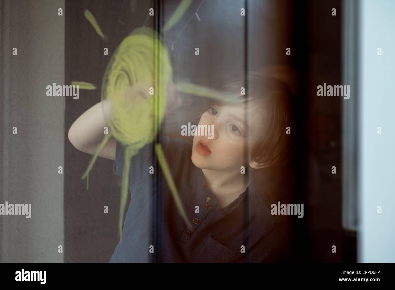 Boy drawing sun on glass Stock Photo - Alamy