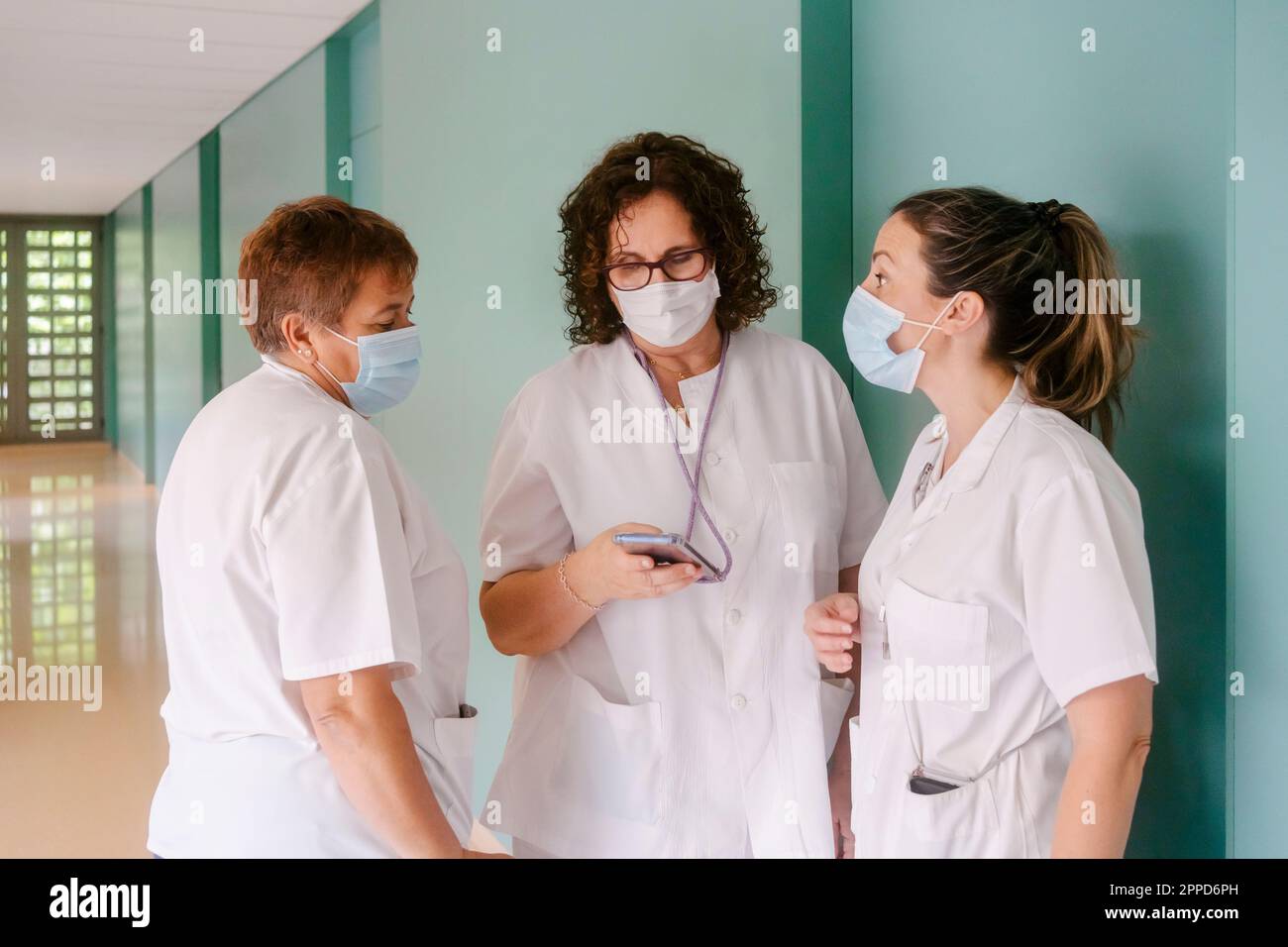 Nurses wearing protective face masks talking to each other at hospital ...