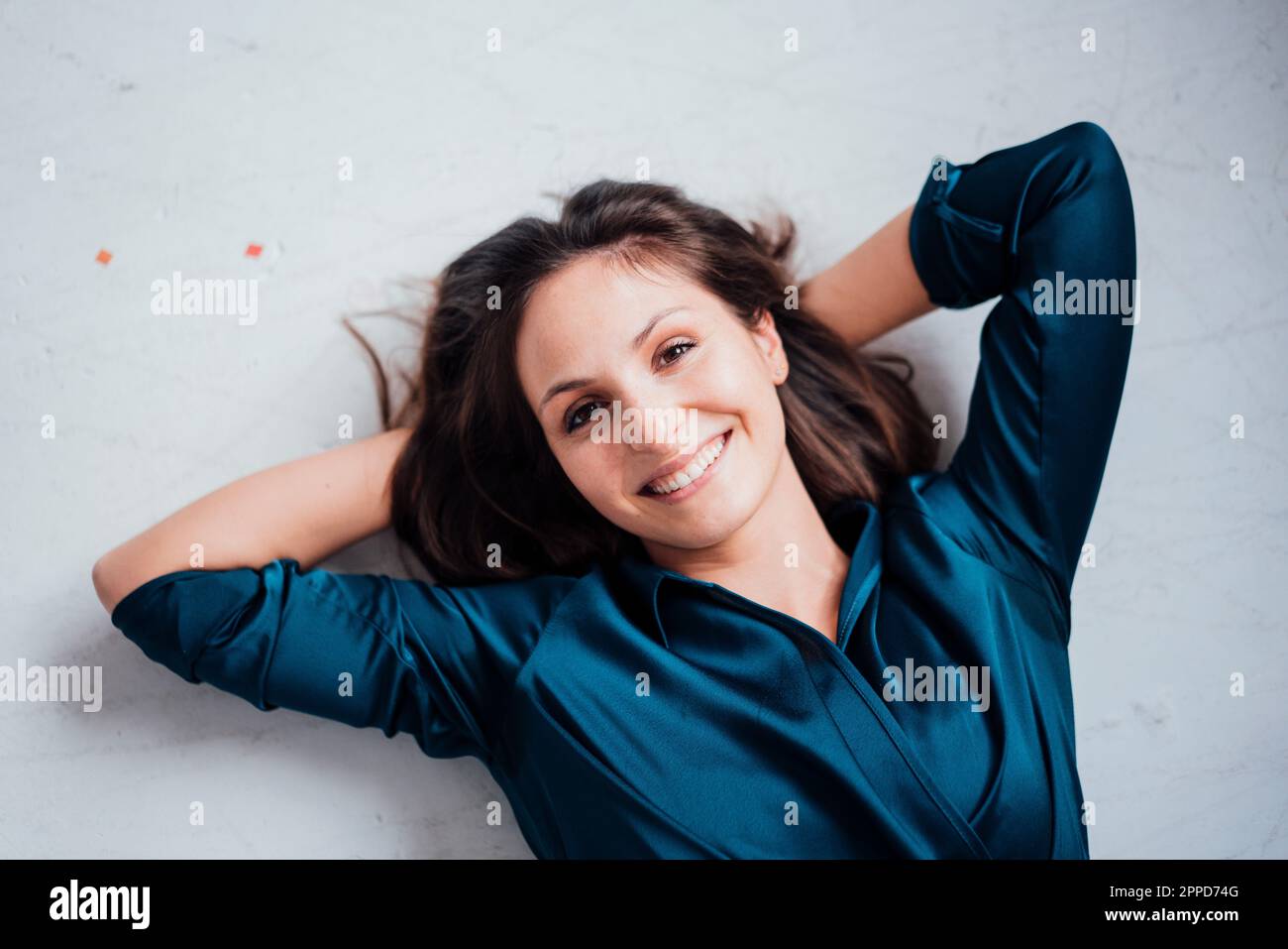 Happy young woman with hands behind head lying down on floor Stock ...
