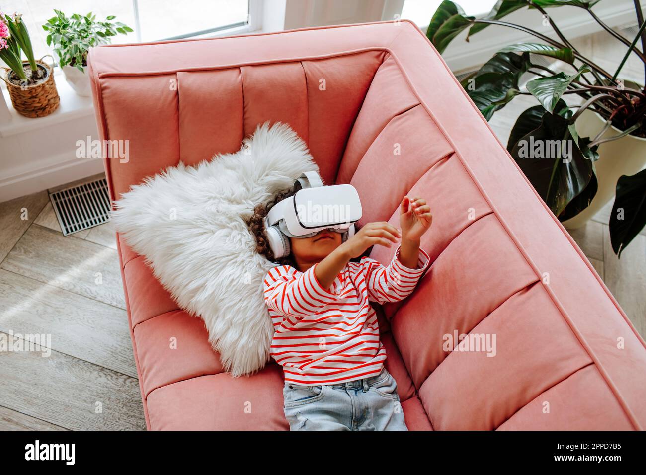 Girl wearing virtual reality simulator gesturing and lying on sofa Stock Photo - Alamy