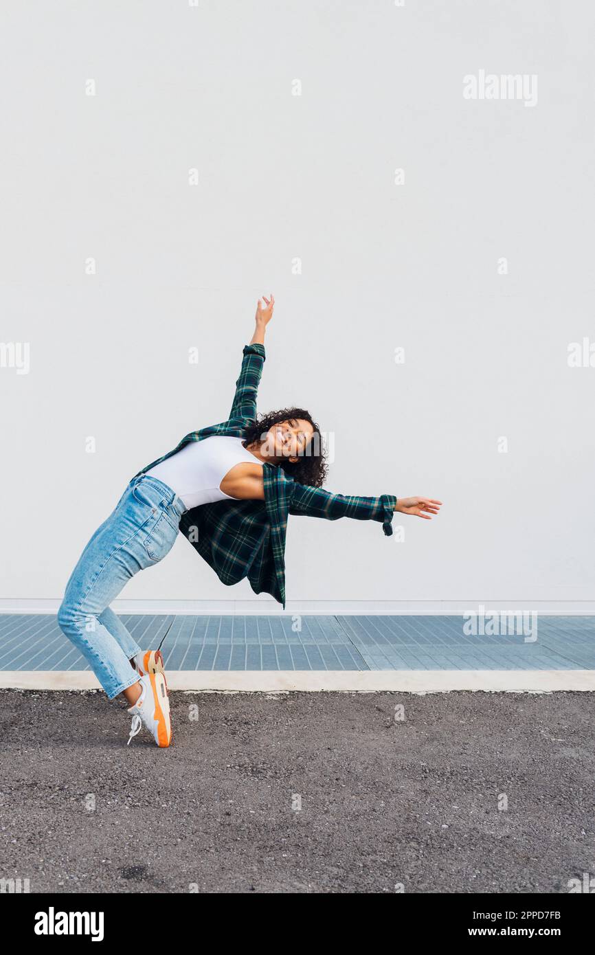 Happy woman dancing and bending over backwards in front of wall Stock ...