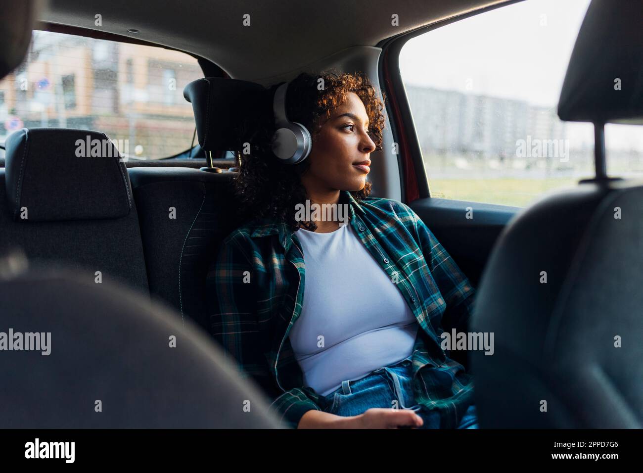Thoughtful woman wearing bluetooth headphones in car Stock Photo - Alamy