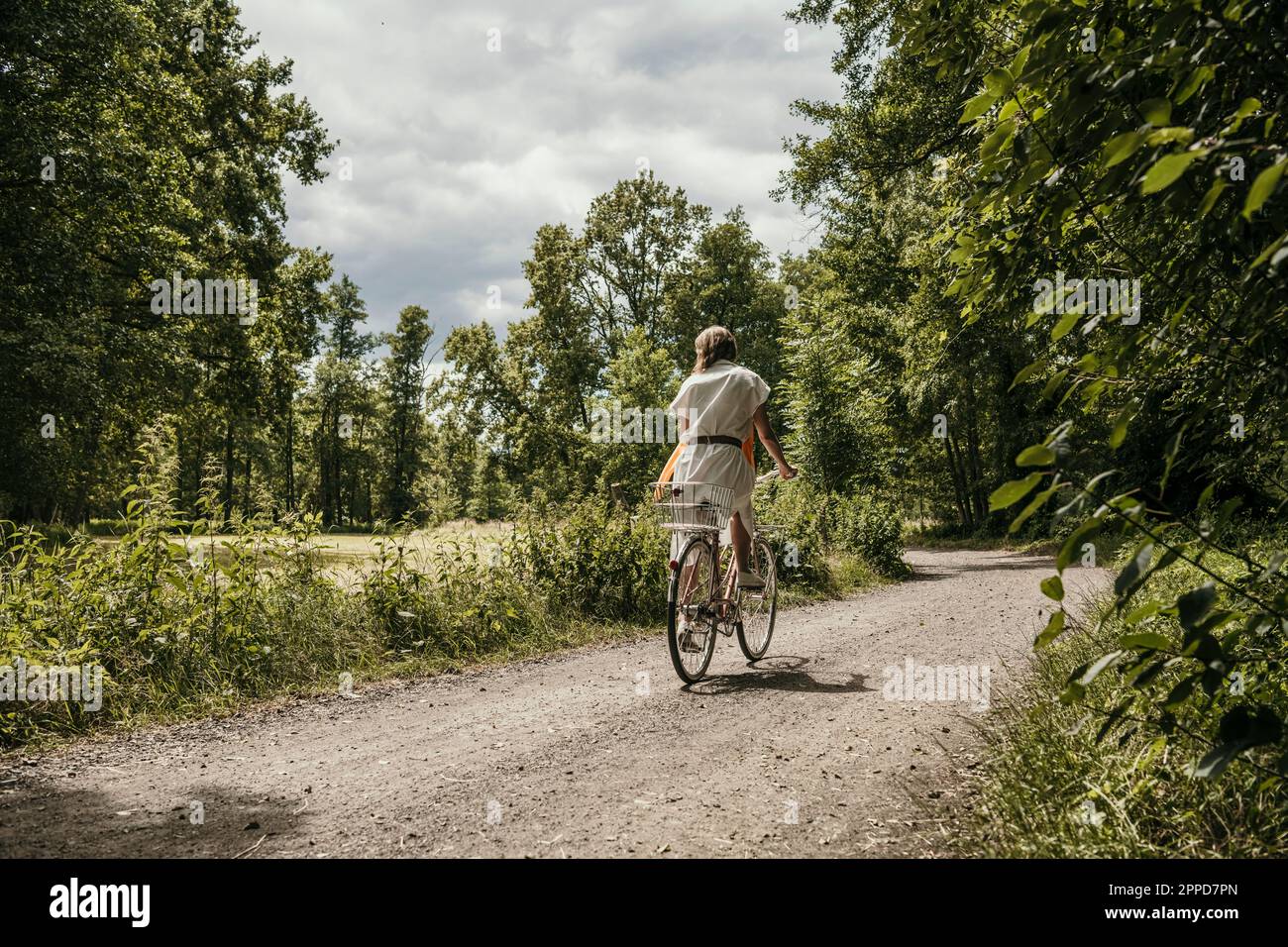Woman riding cycle on dirt road Stock Photo - Alamy