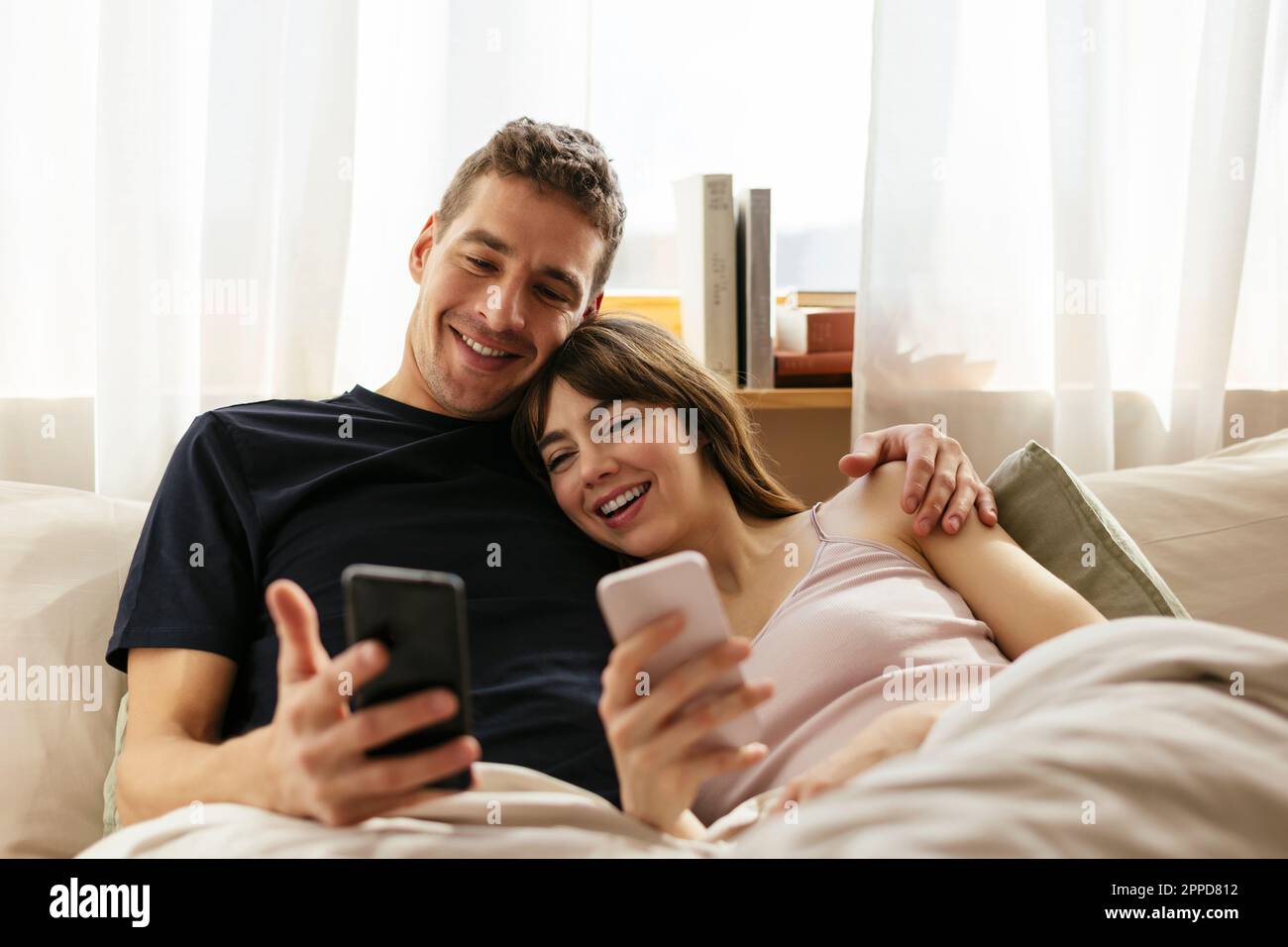 Couple phones bed hi-res stock photography and images - Alamy