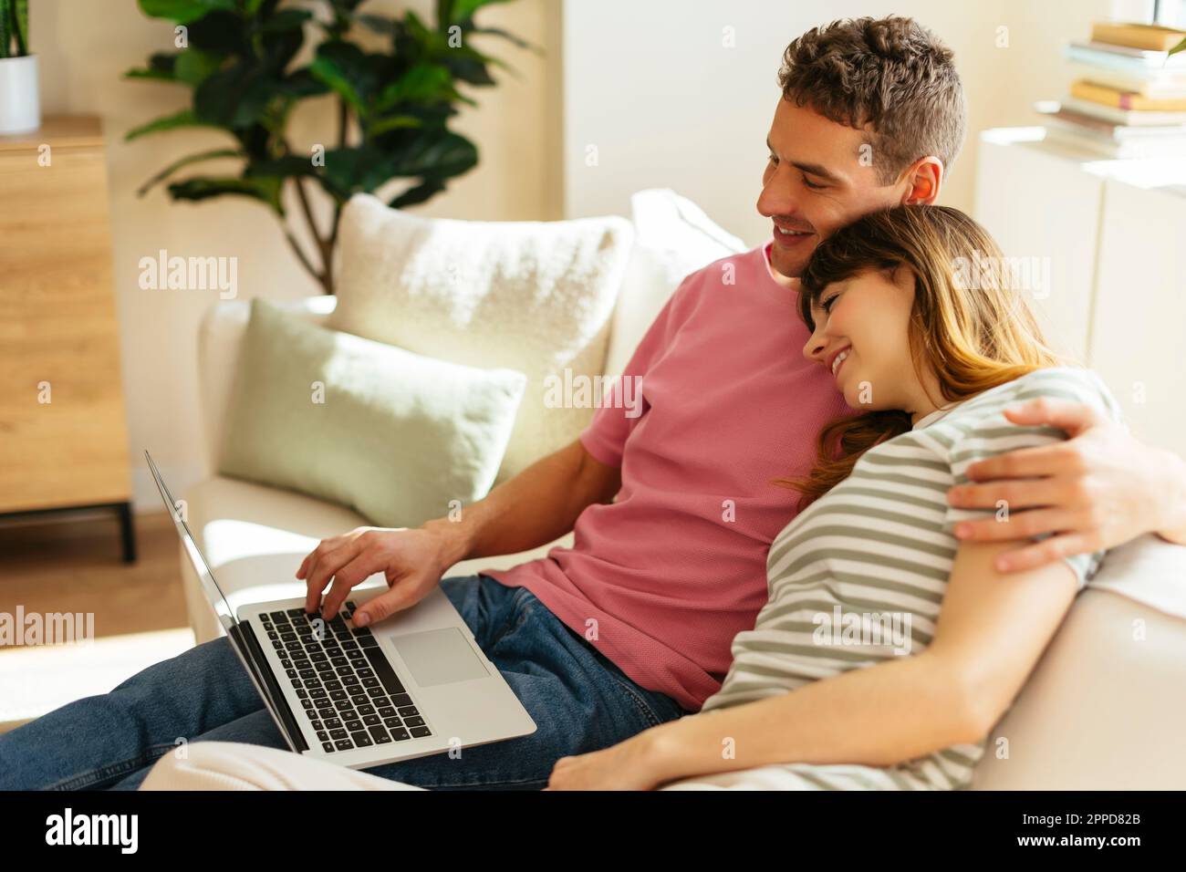 Girlfriend leaning head on boyfriend's shoulder using laptop at home ...