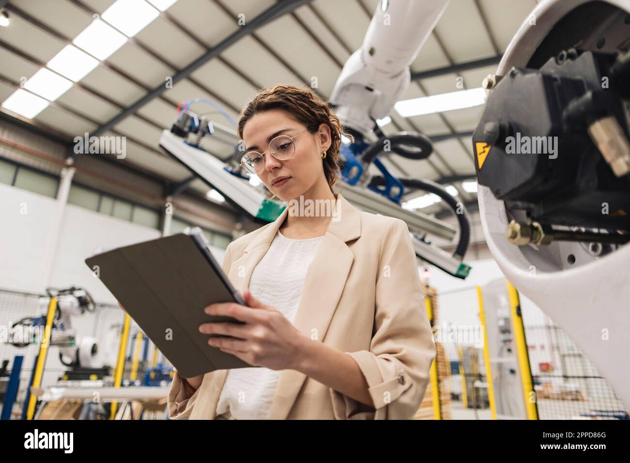 Young engineer using tablet PC in front of robotic arm Stock Photo - Alamy