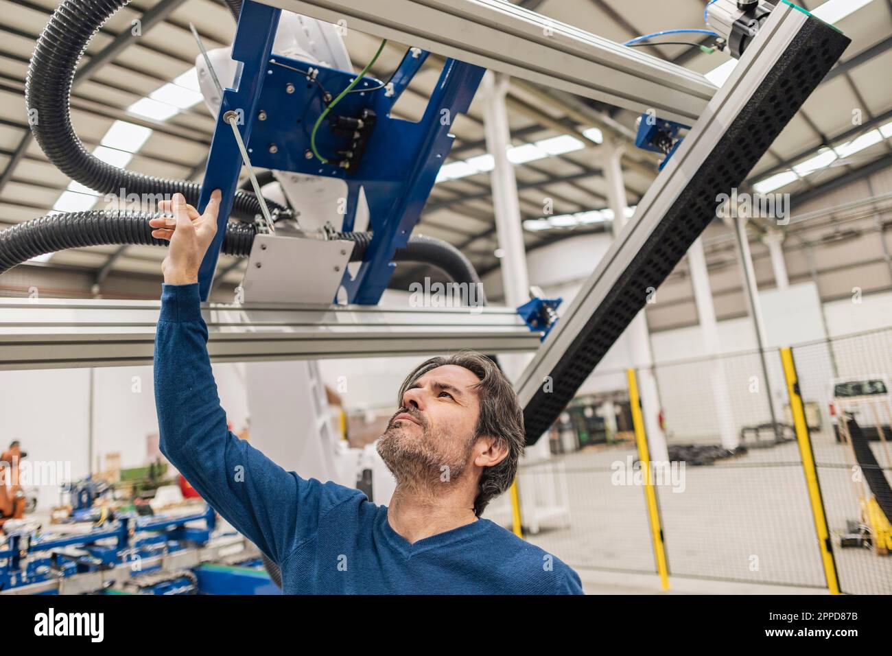 Engineer touching and examining robotic arm in factory Stock Photo - Alamy