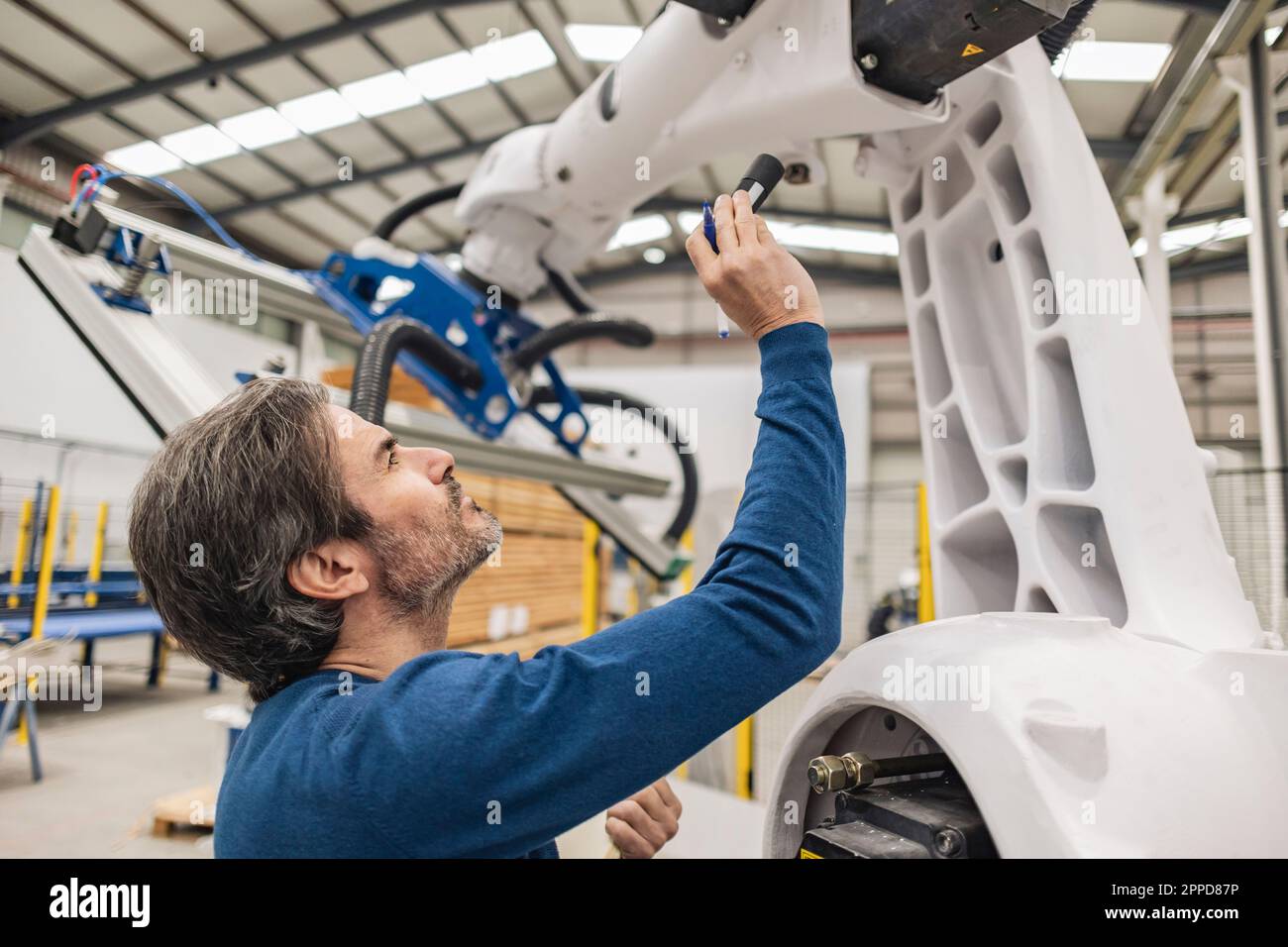 Engineer examining robotic arm with flashlight in industry Stock Photo ...