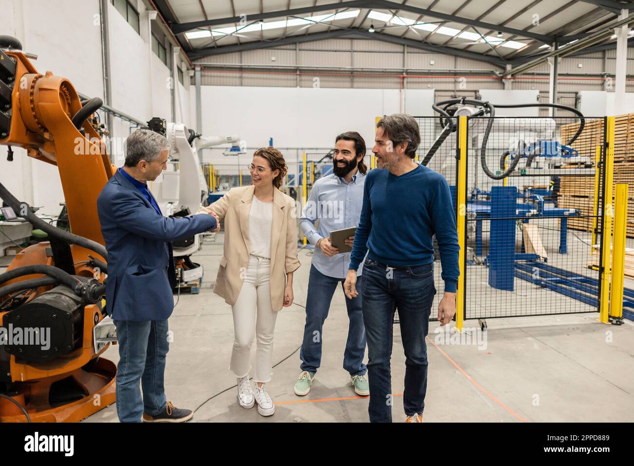 Happy young engineer shaking hands with colleague in robotic industry ...