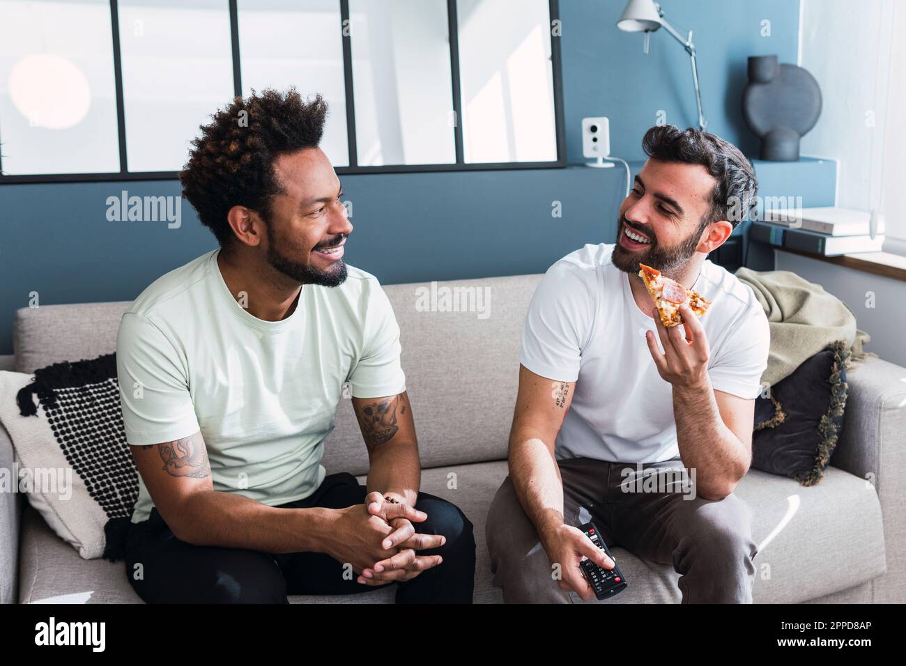 Multiracial friends talking to each other sitting on sofa at home Stock ...