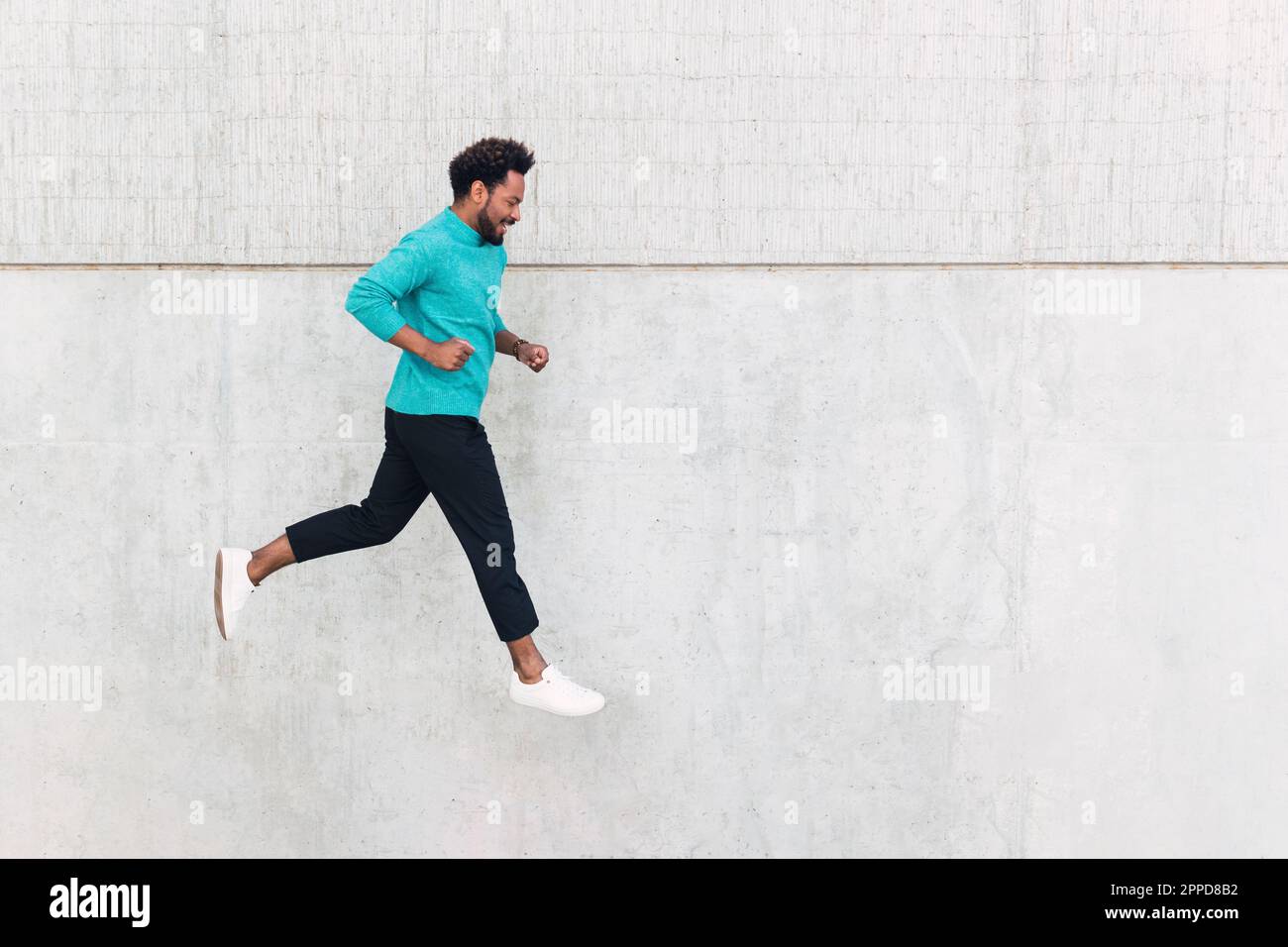 Man jumping in front of concrete wall Stock Photo - Alamy