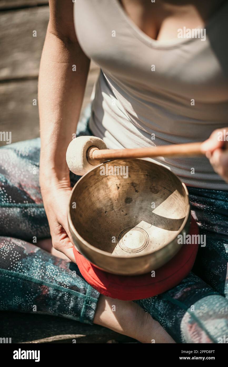 Woman sitting cross-legged holding Tibetan singing bowl Stock Photo - Alamy
