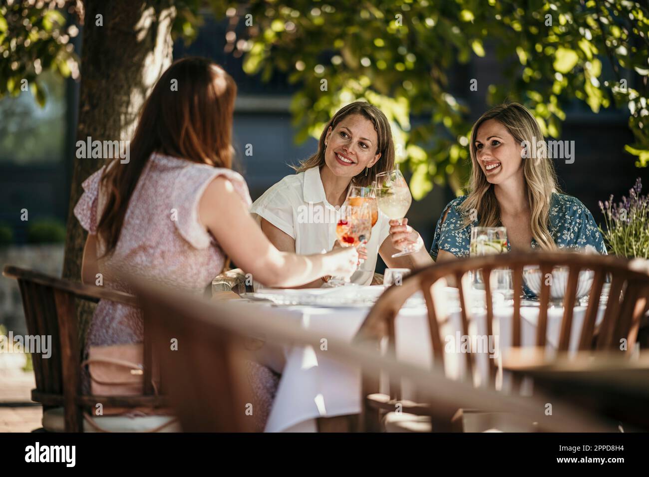 Smiling women enjoying drinks sitting at dining table in restaurant ...