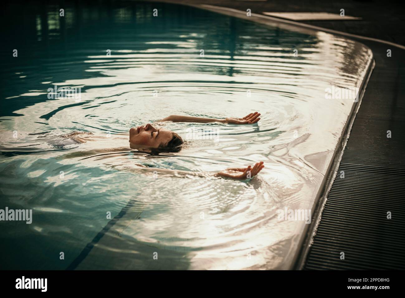 Woman with arms raised floating in swimming pool Stock Photo - Alamy