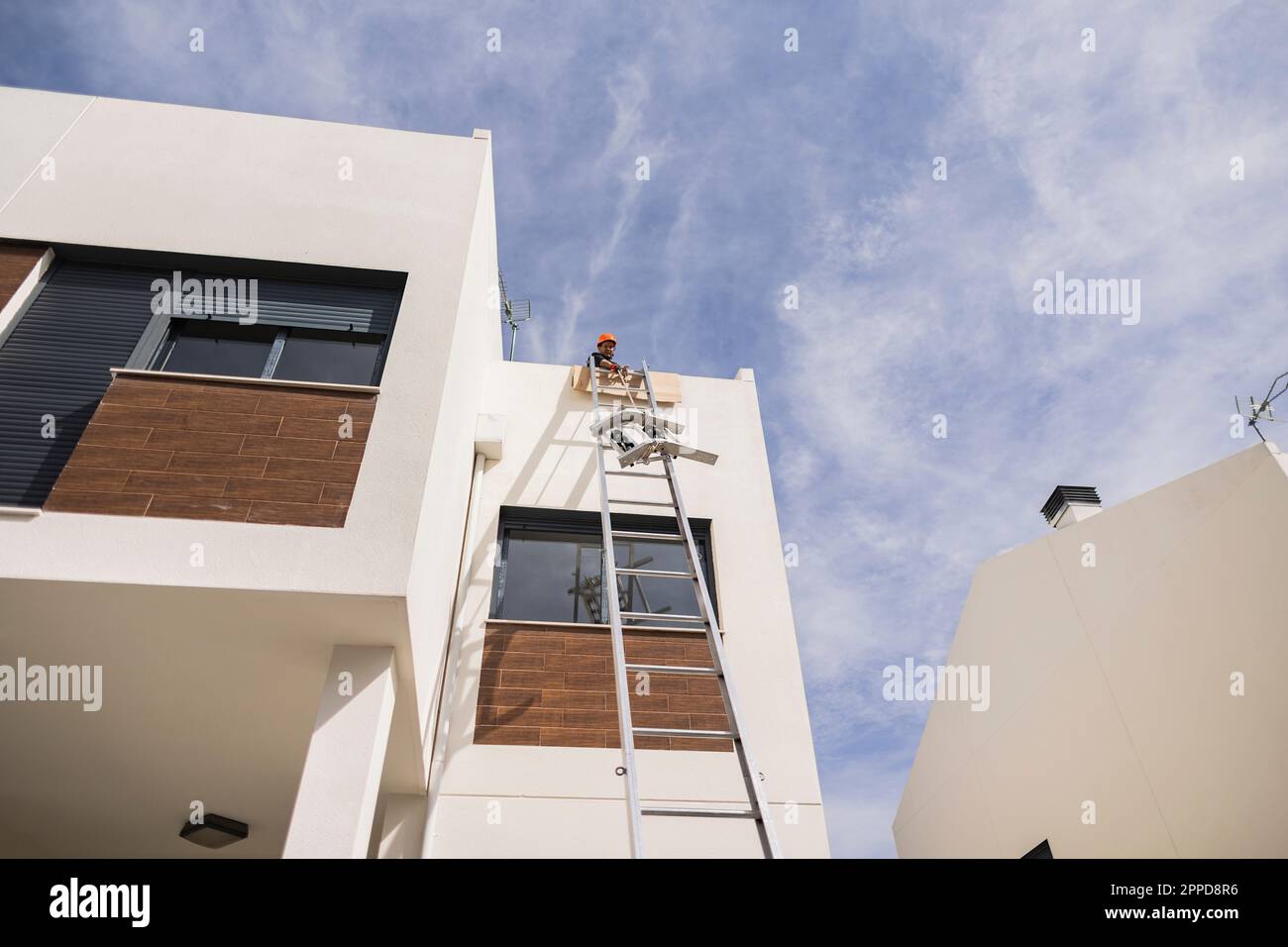 Technician pulling equipment with rope on roof Stock Photo - Alamy