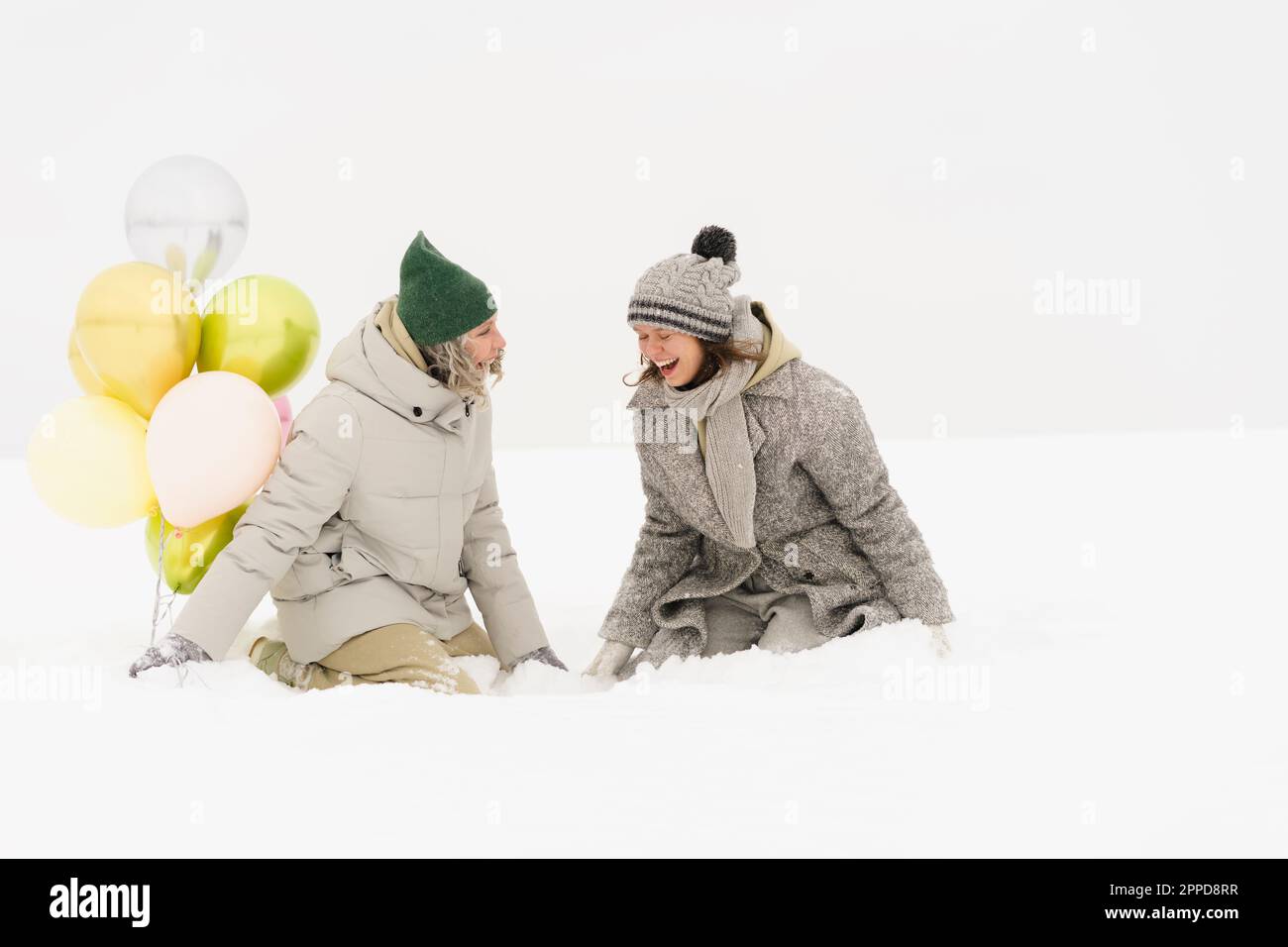 Happy women with balloons enjoying in snow Stock Photo - Alamy