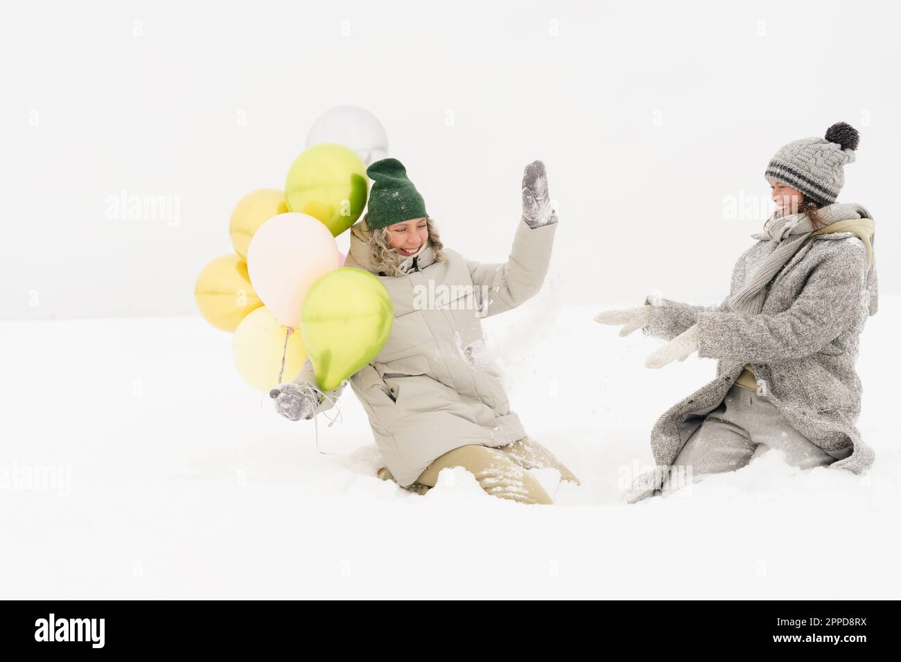Happy friends having fun with balloons in snow Stock Photo - Alamy