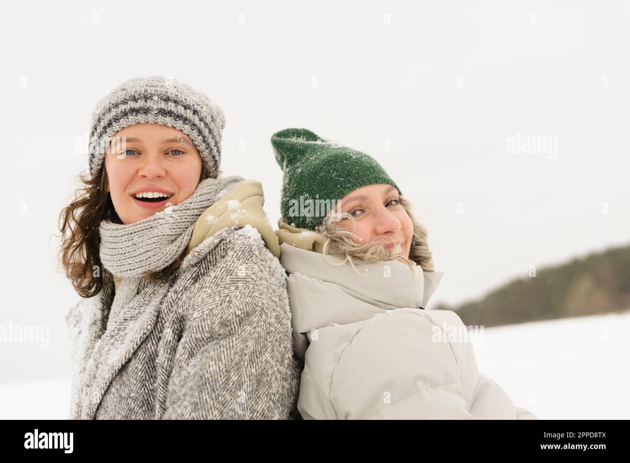 Happy friends wearing knit hats enjoying in snow Stock Photo - Alamy