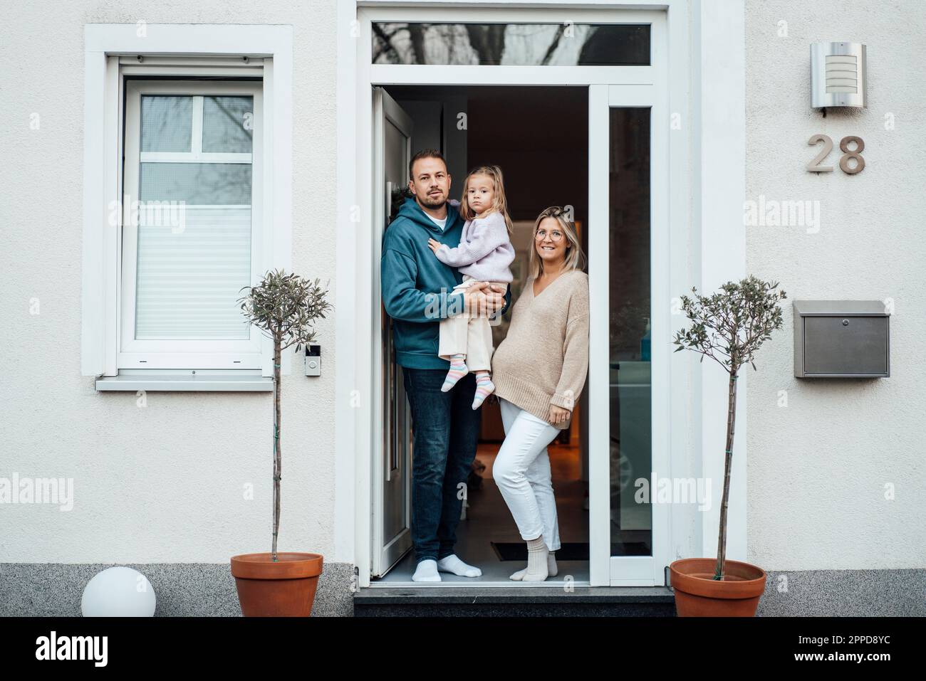 Happy family standing at front door Stock Photo - Alamy